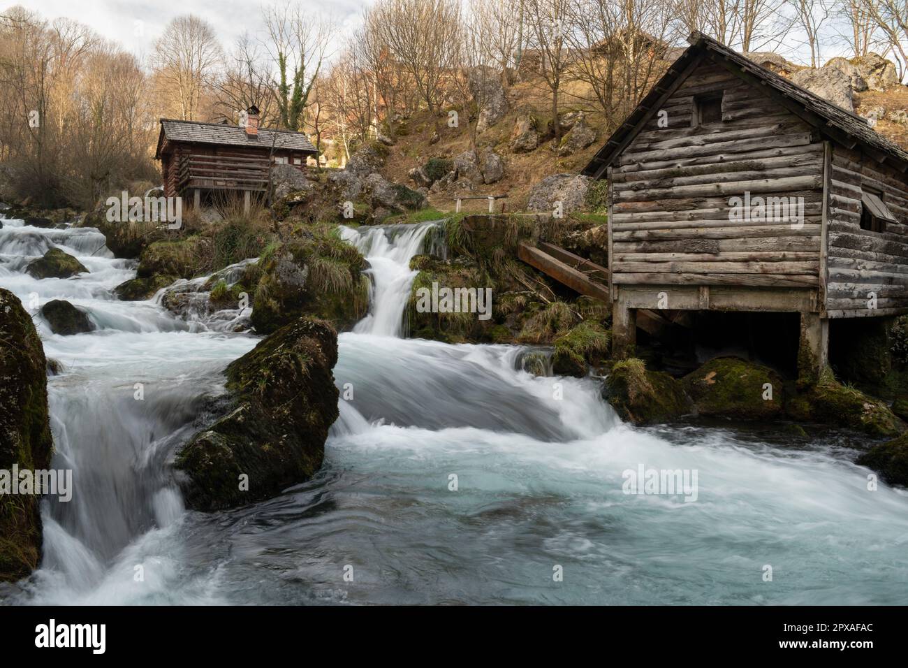 Mountain river with mossy rocks and wooden watermills in long exposure ...
