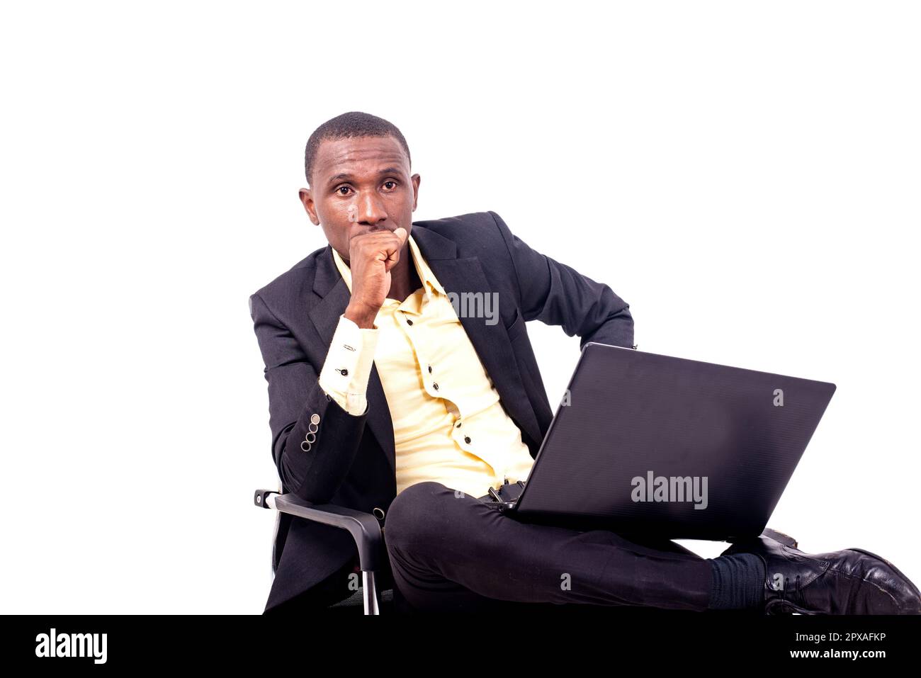 Thinking businessman holding hand over mouth sitting on chair with ...