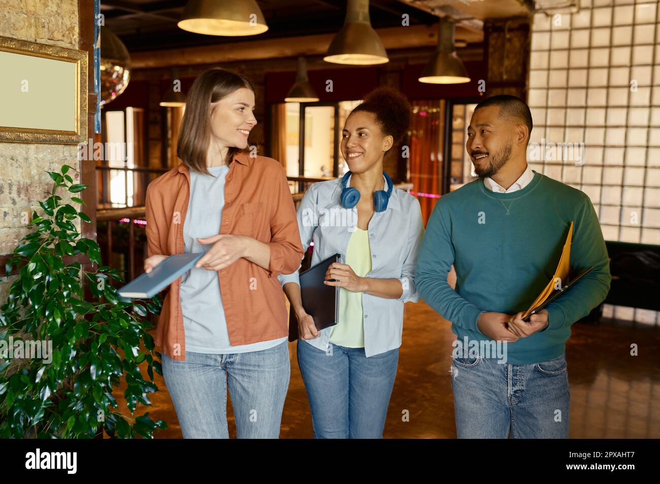 Happy cheerful coworkers chatting and laughing at office openspace ...