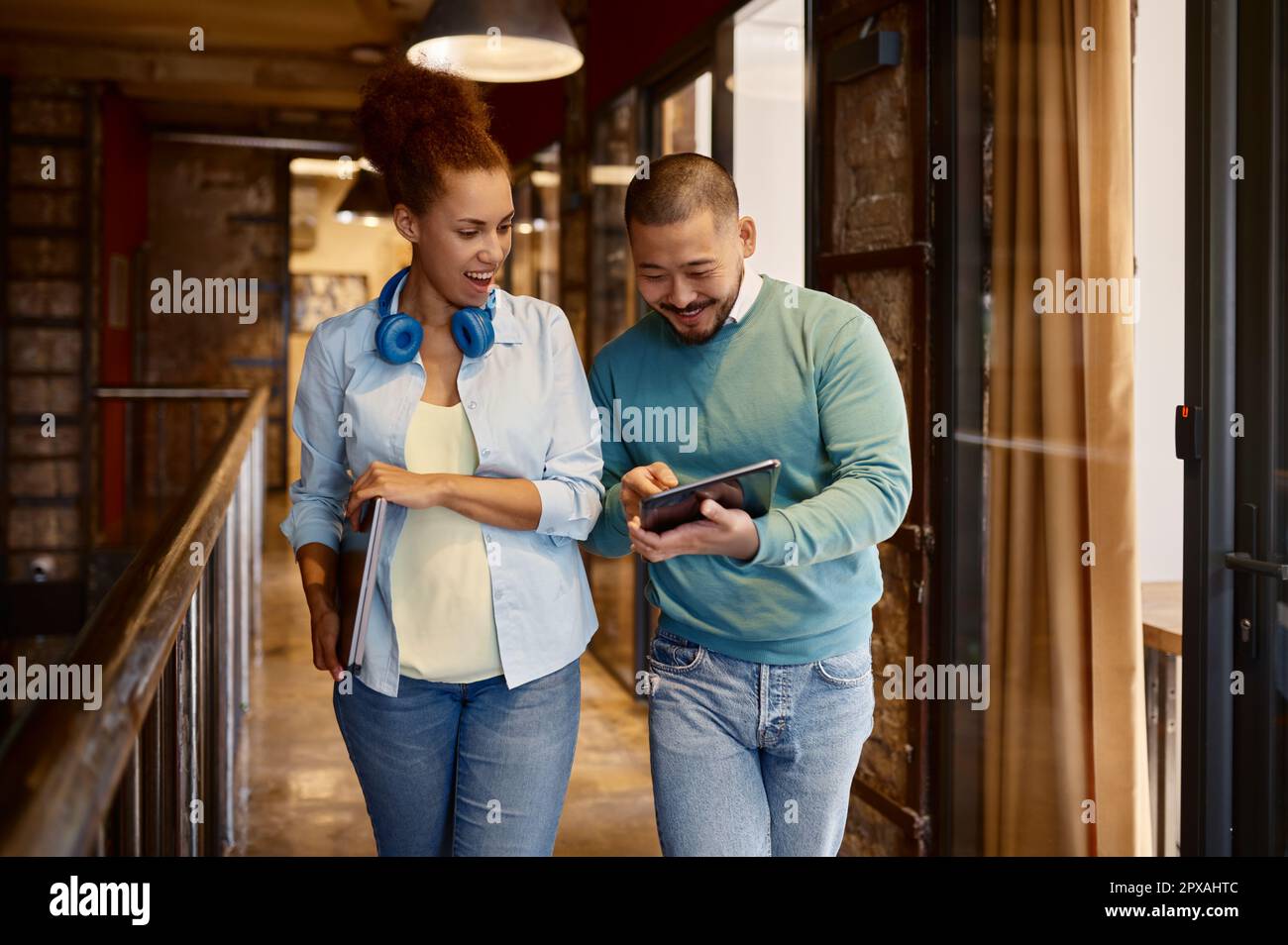 Diverse colleagues talking in hallway of modern coworking office ...