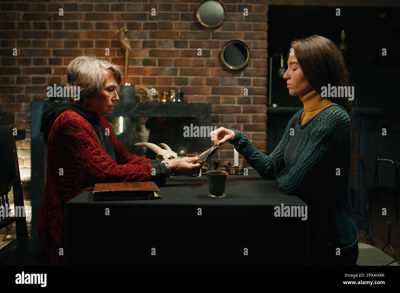 Old mature soothsayer holding divination tarot cards in front of female ...