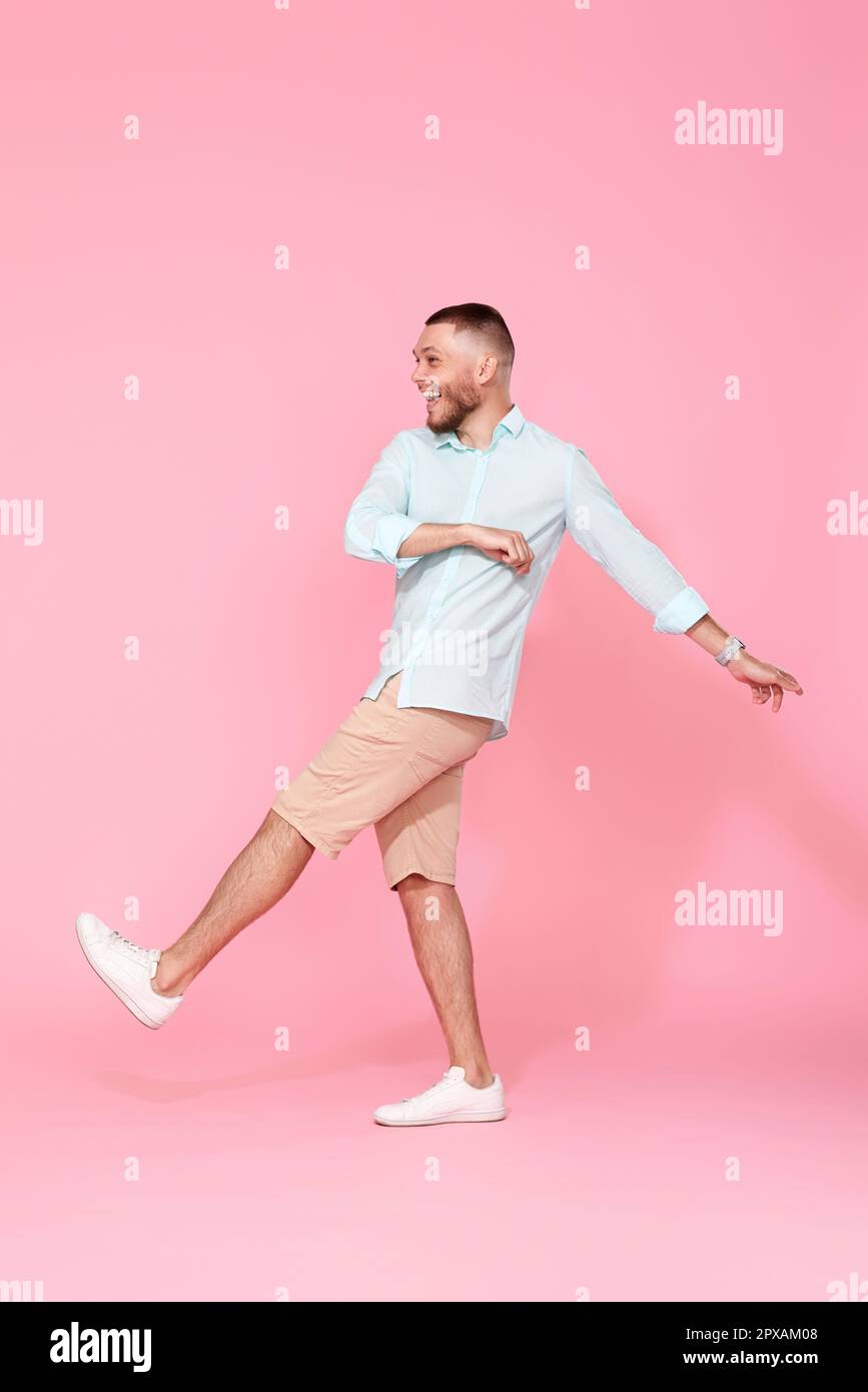 cheerful young happy man dance on pink background. vacation summer ...