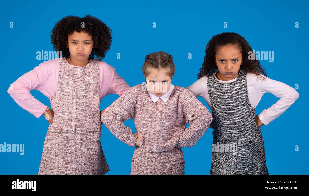 Angry sad offended international little girls in casual look menacingly ...