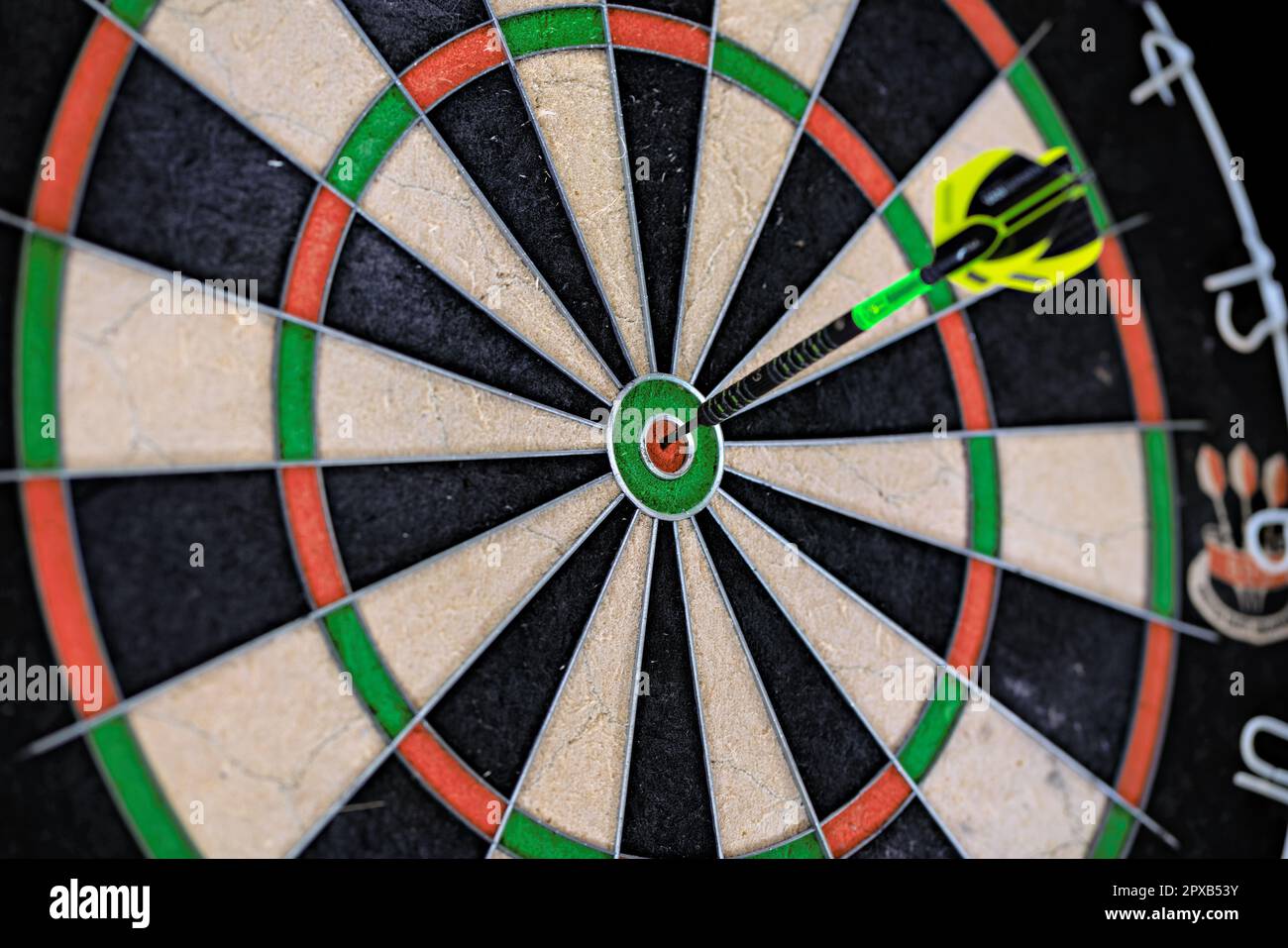 Single black and green dart stuck in the bullseye of a dartboard. Close ...