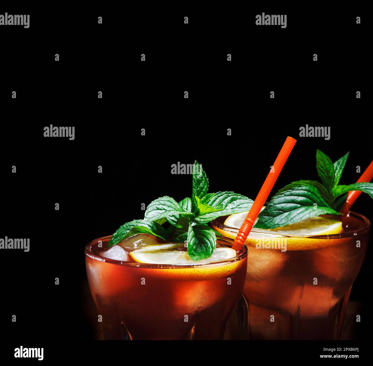 Cuba libre cocktail with ice, mint and lemon over black background ...