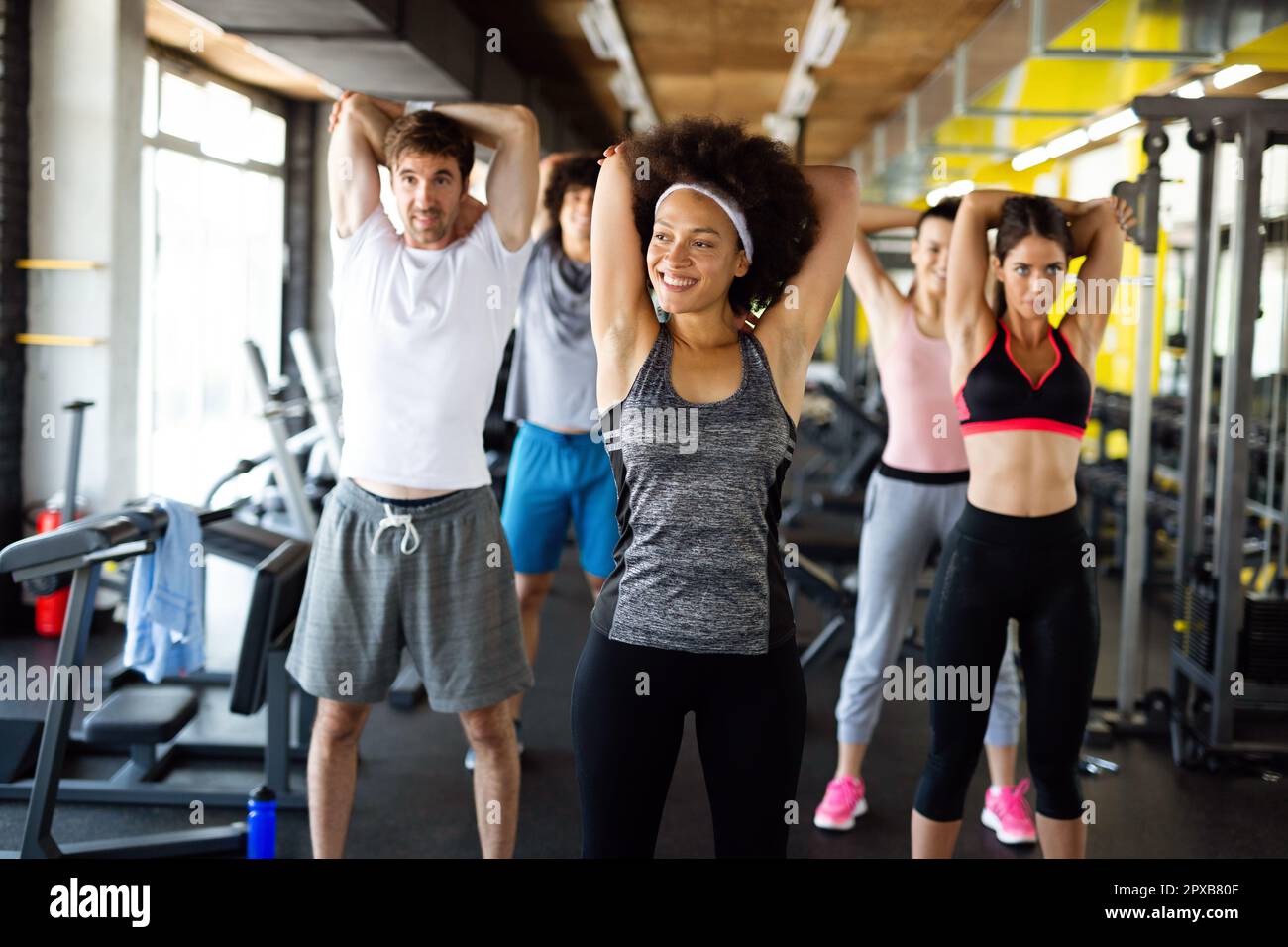 Group of young fit people, friends doing exercises in gym to stay ...