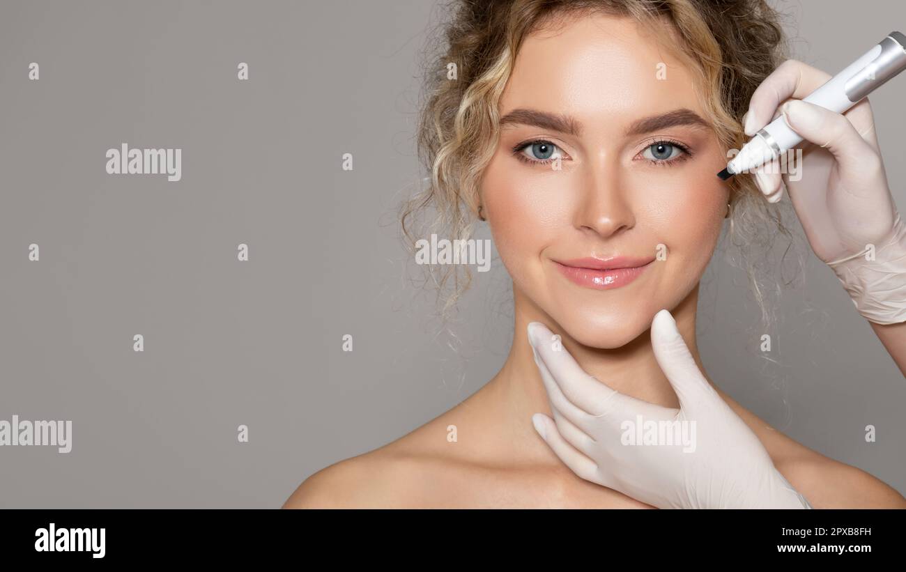 Doctor drawing marks on young woman's face for cosmetic surgery ...