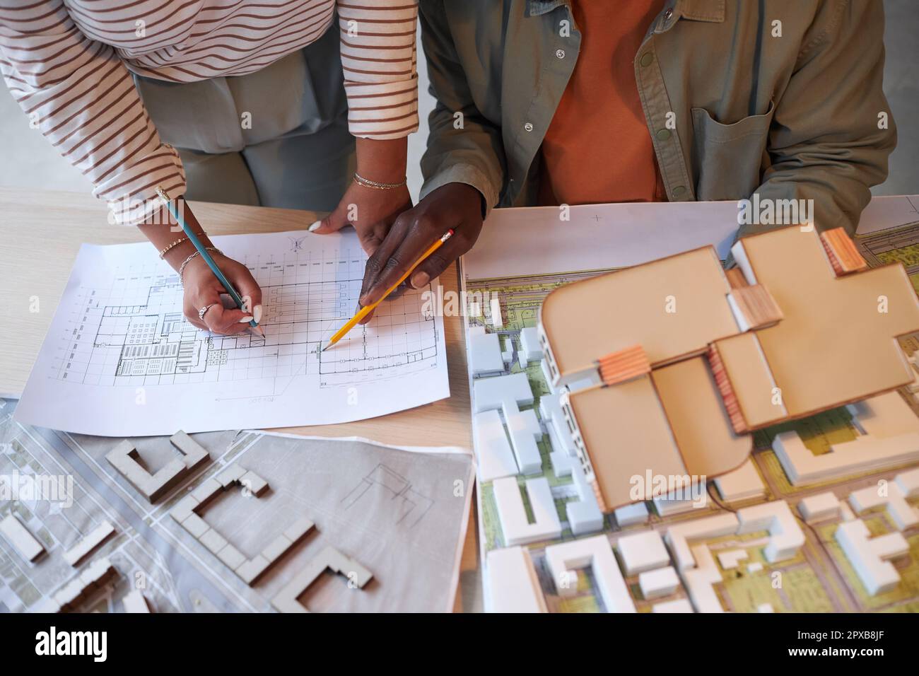 High angle view of designers drawing blueprint in team while sitting at ...