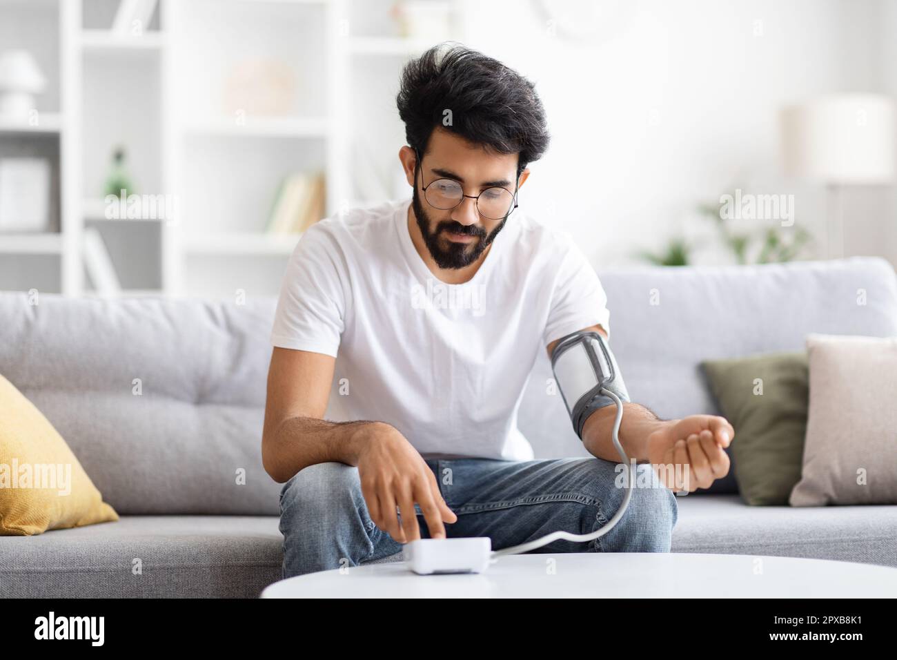 Young Indian Guy Checking Blood Pressure With Upper Arm Monitor At Home ...