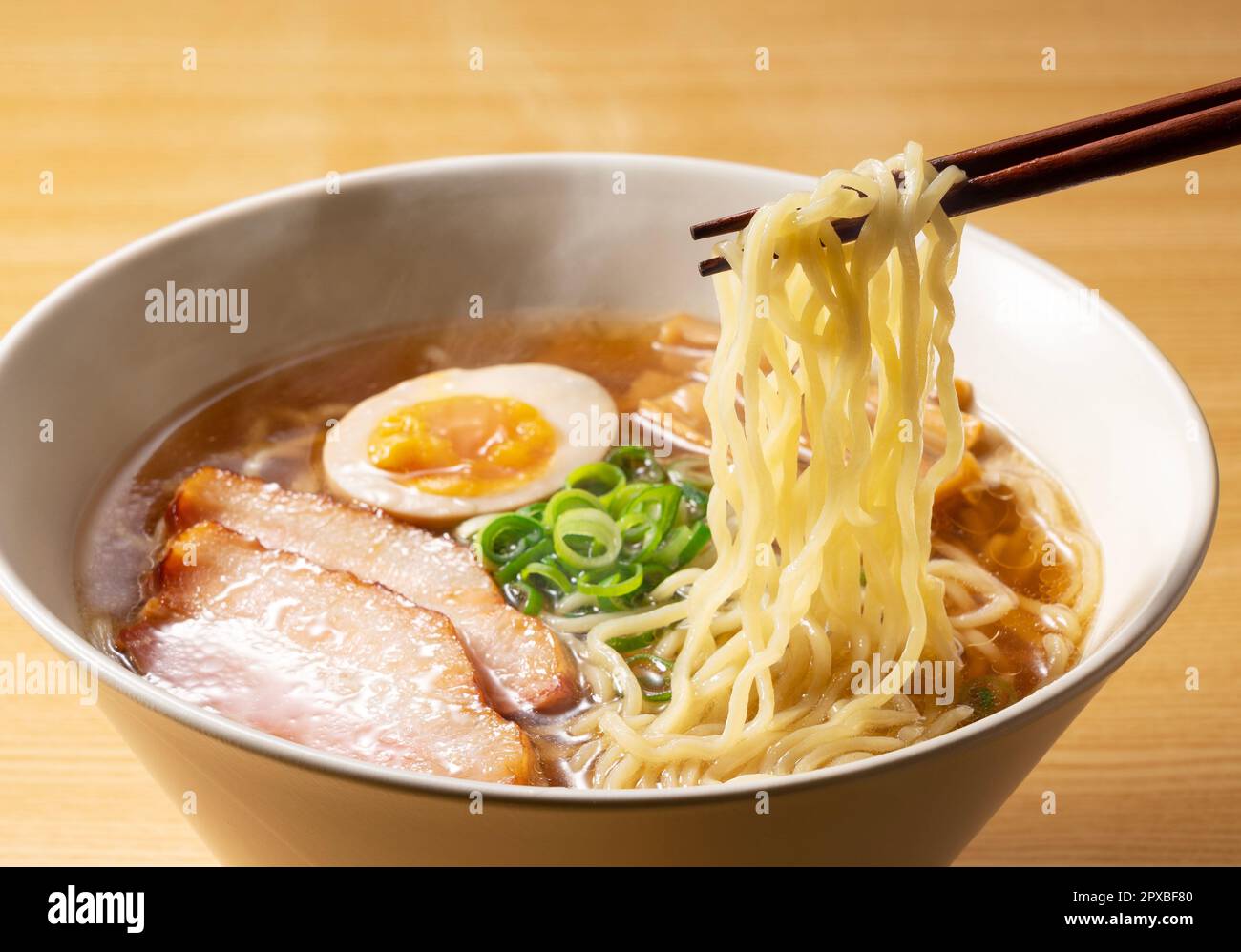 Hot ramen noodles with steamy water on the table. Scoop it up with ...
