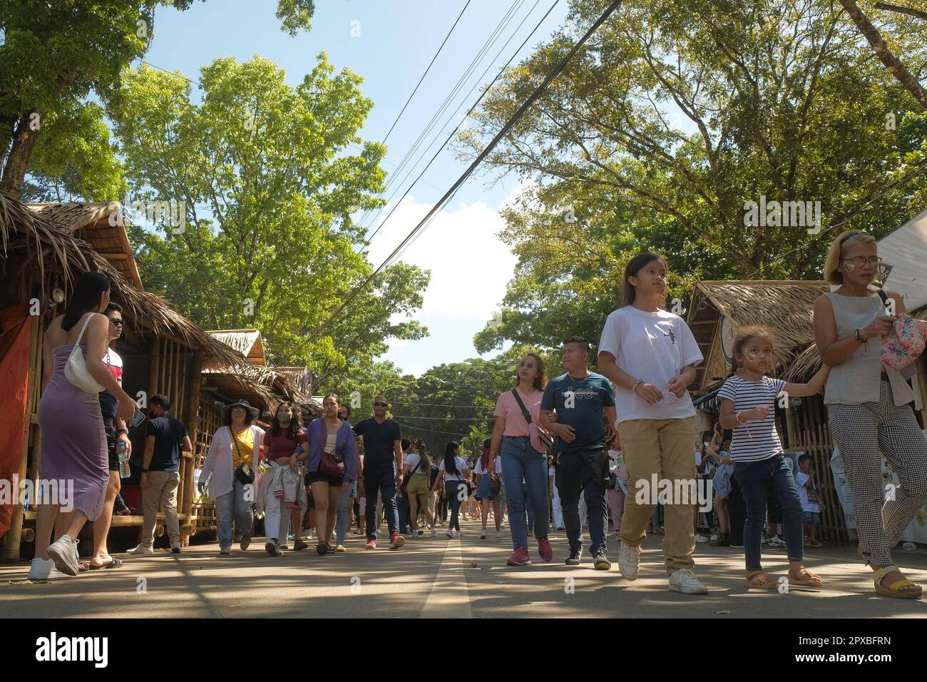 Malaybalay City, Philippines - people walk past a busy tree-lined ...