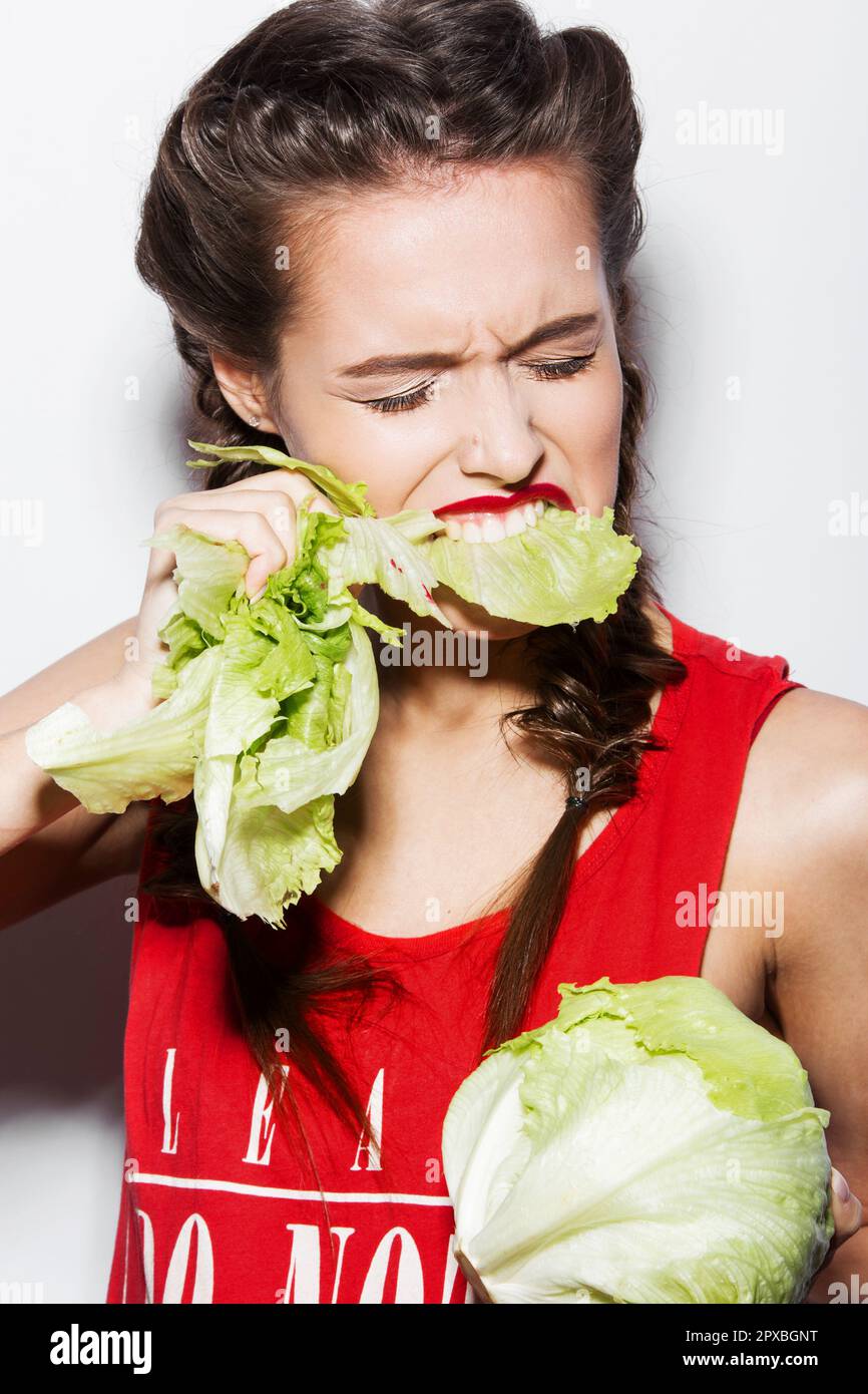 Daring funny girl with braids and red lips, emotional eating cabbage ...