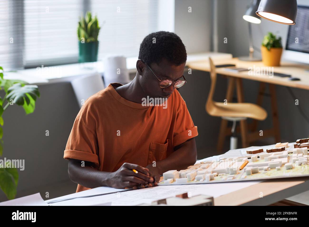 African American architect in eyeglasses concentrating on his work over ...