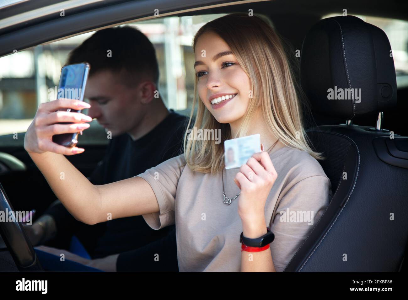 Happy smiling girl takes a selfie with a new drivers license, sitting ...