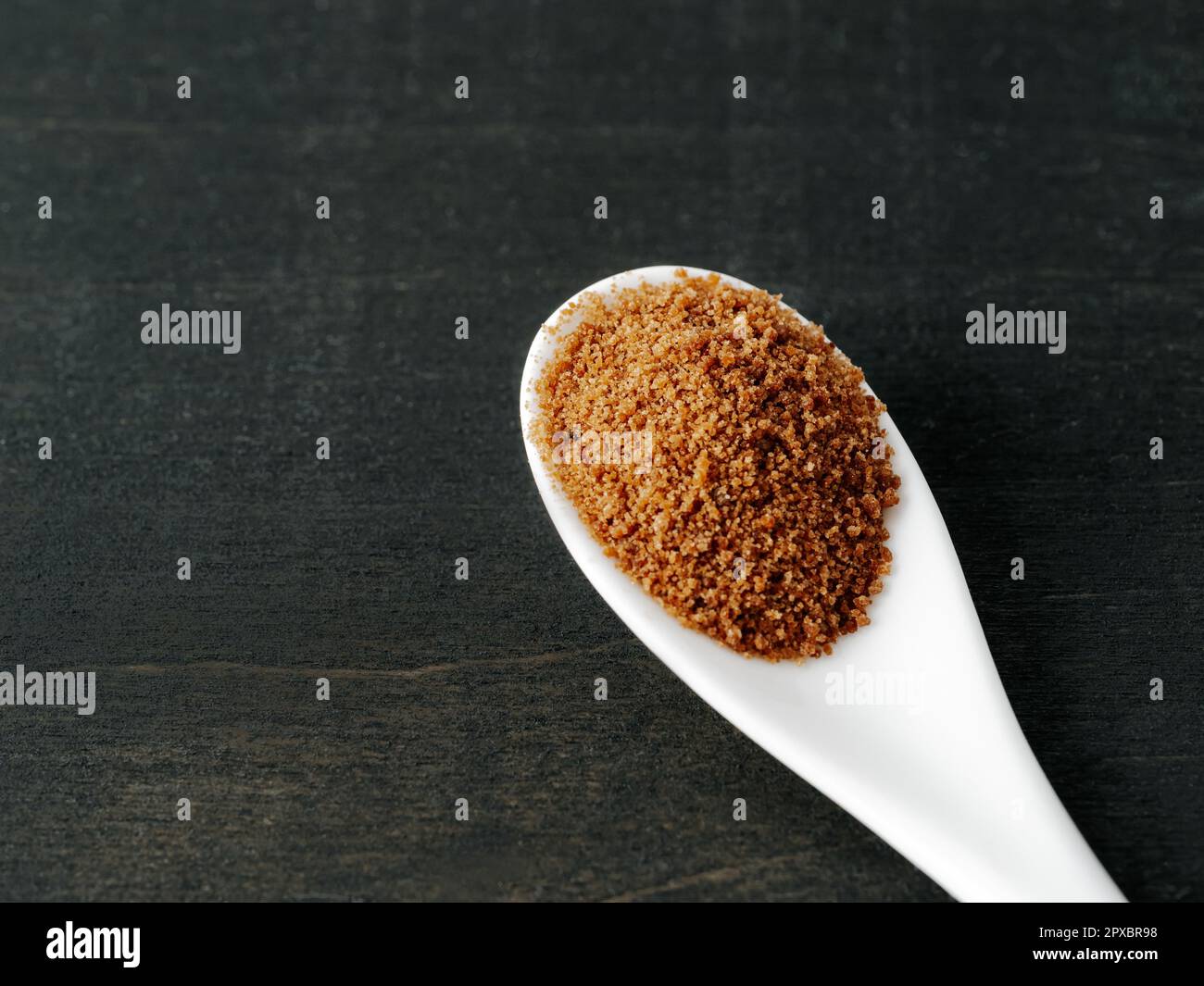 Spoon of coconut brown sugar on dark wooden background. Top view of ...