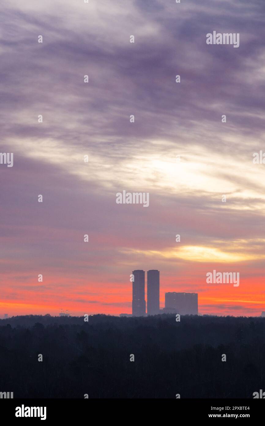 purple clouds in dawn sky over city park and towers on cold morning ...