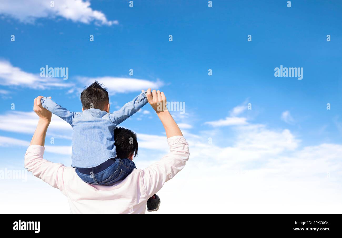 Father giving son piggyback ride on his shoulders and looking the cloud ...