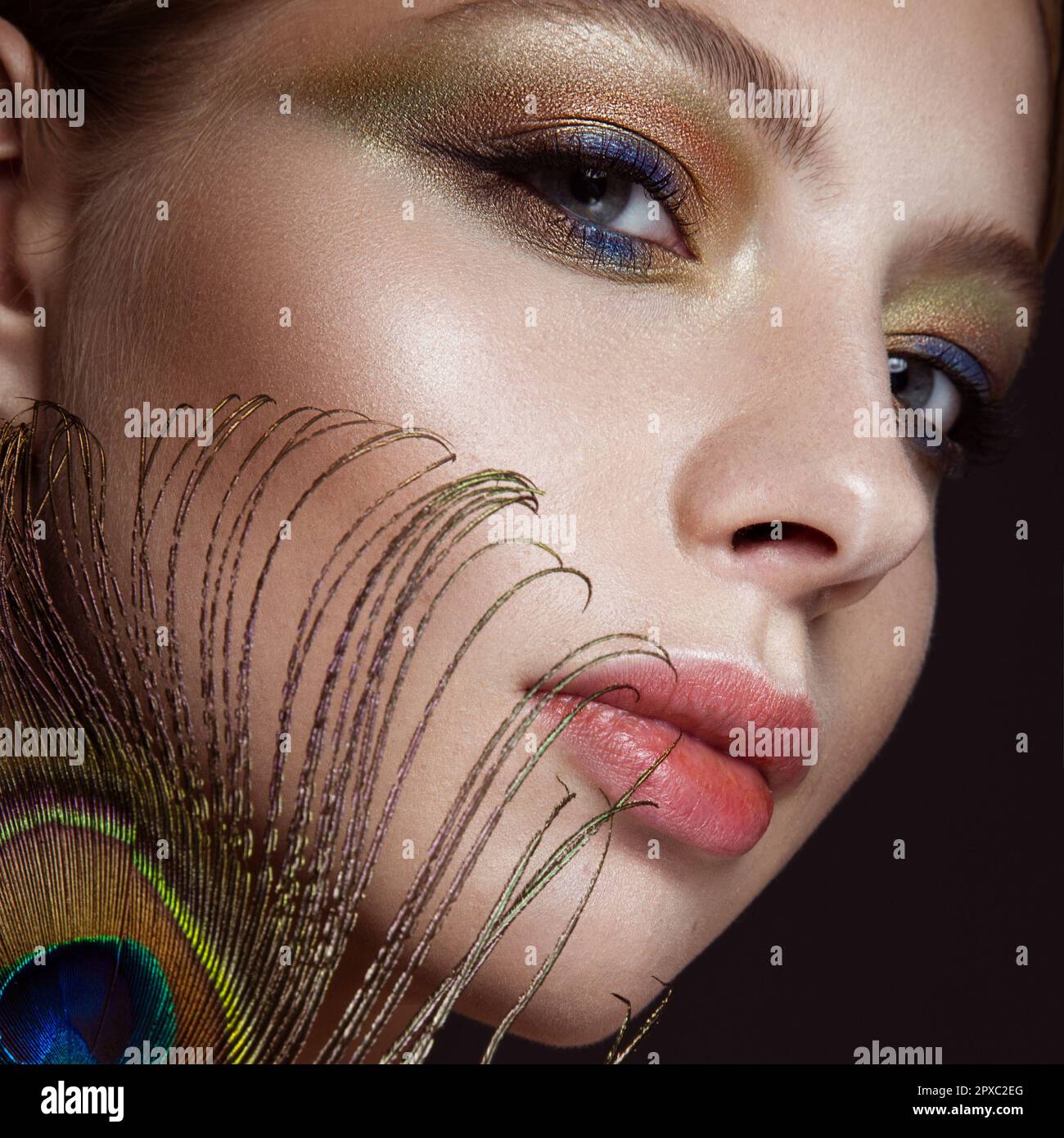 Beautiful girl with bright colored makeup and peacock feather on her ...