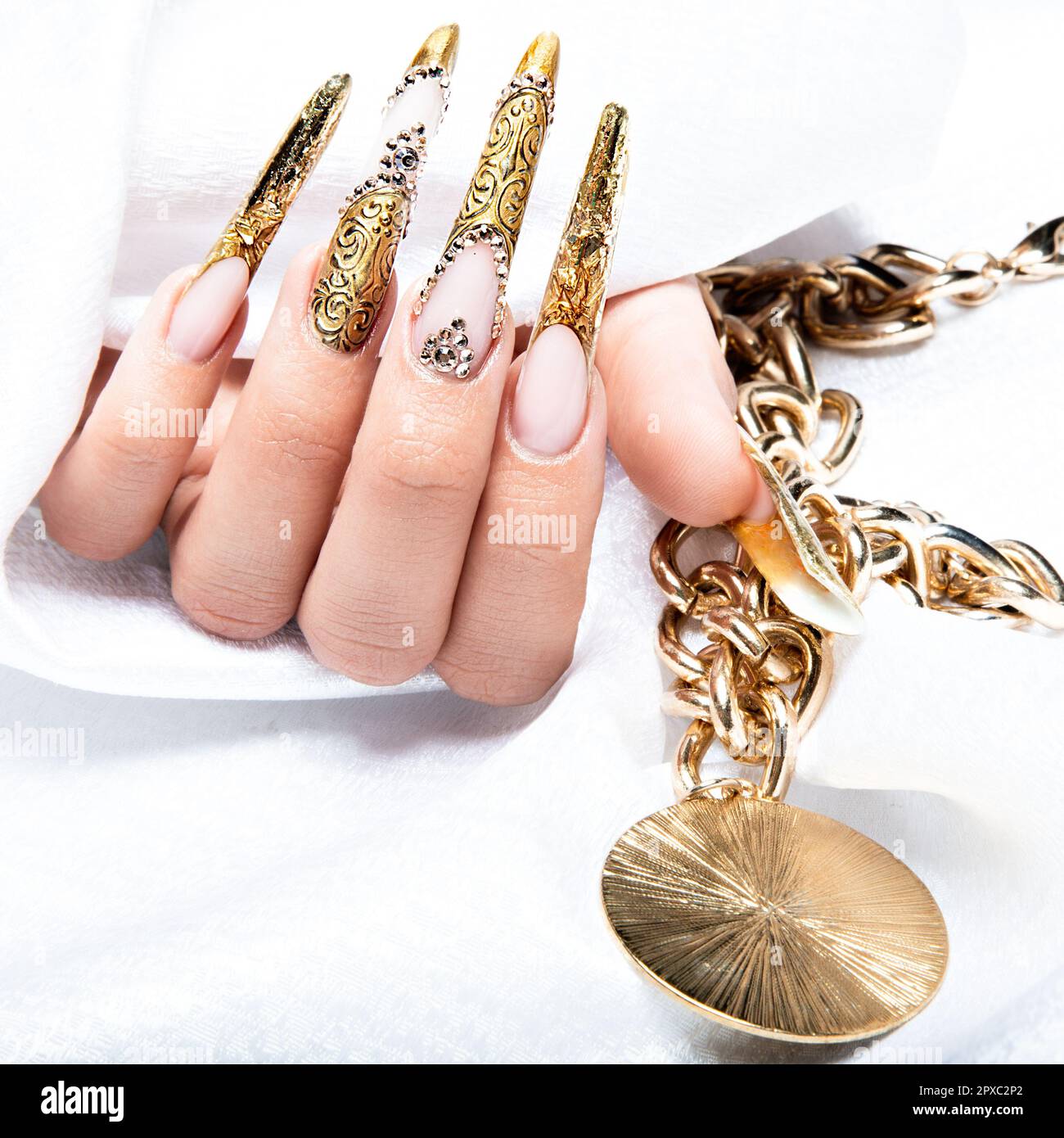 Beautiful long nails in a gold design with rhinestones Stock Photo - Alamy