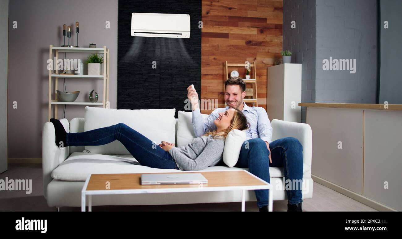 Happy Family Couple Using Air Conditioner. Apartment AC Stock Photo - Alamy