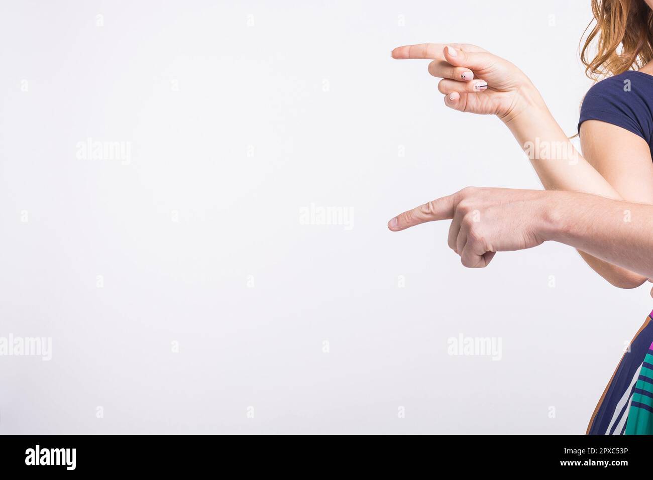 Couple pointing at the left corner with fingers standing isolated over ...