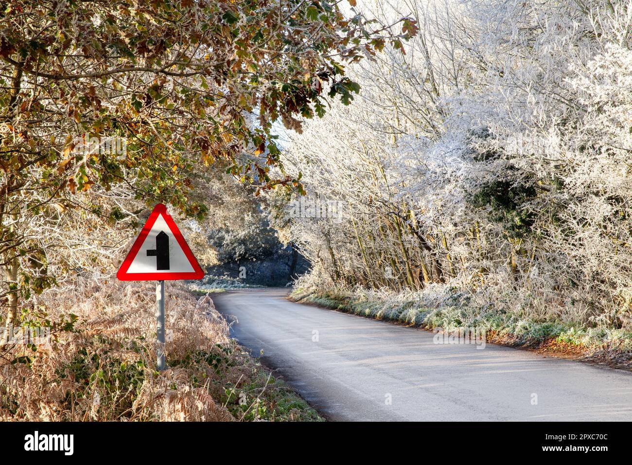 Frozen winter rural road with triangle warning sign and lined with ...