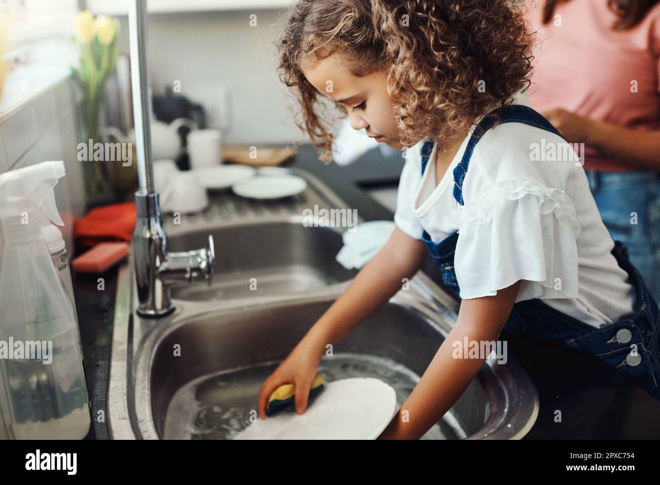 Moms Got Me Doing The Dishes An Adorable Young Girl Standing And Washing The Dishes In The