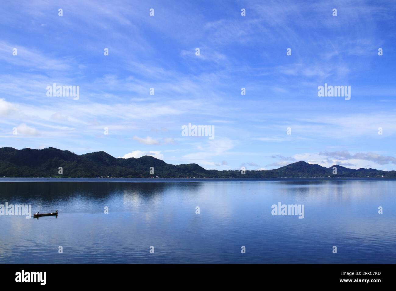 A boat in the middle of a very shady lake, with shades of blue all ...