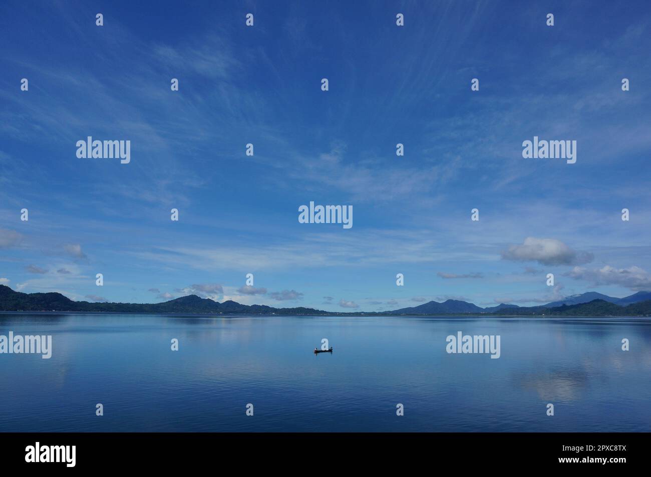 A boat in the middle of a very shady lake, with shades of blue all ...
