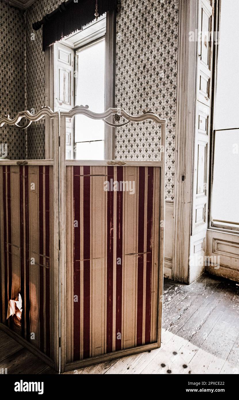 Torn vintage modesty screen in a run down attic room in an English ...