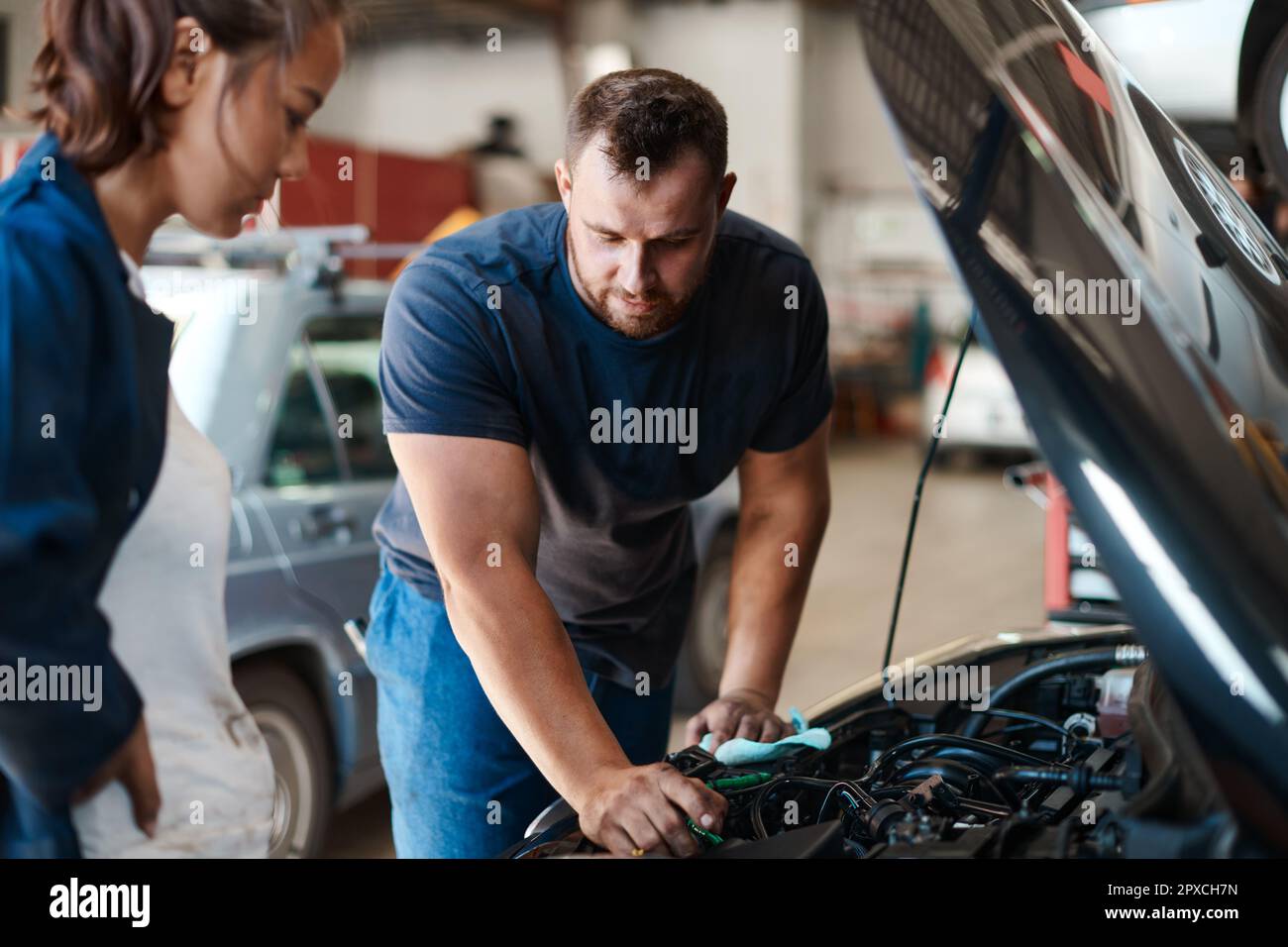 Let us Rev Up your engine. two mechanics working together on a car in ...