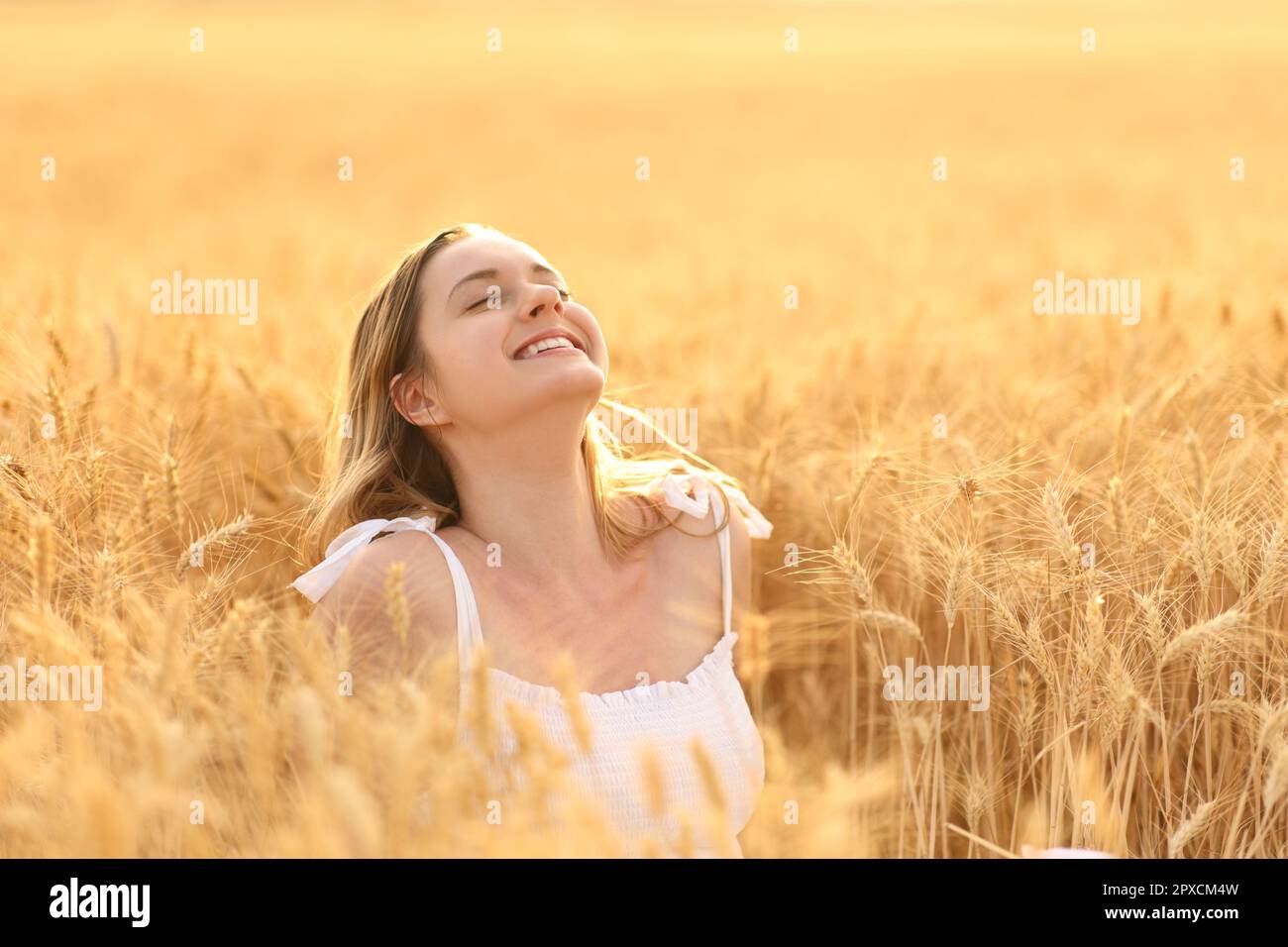 Happy woman breathing fresh air in a golden field Stock Photo - Alamy