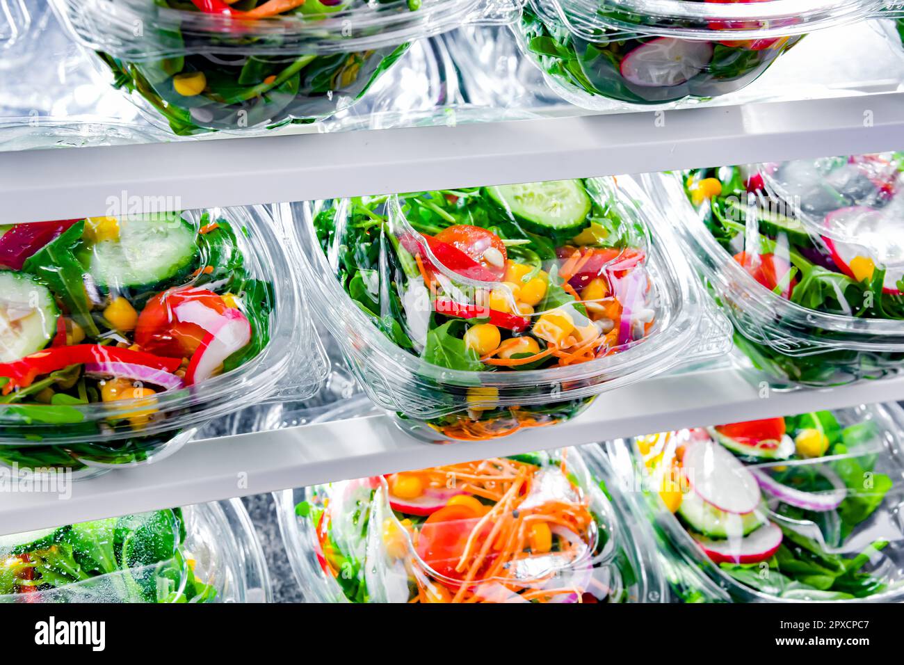 Plastic boxes with pre-packaged vegetable salads, put up for sale in a ...