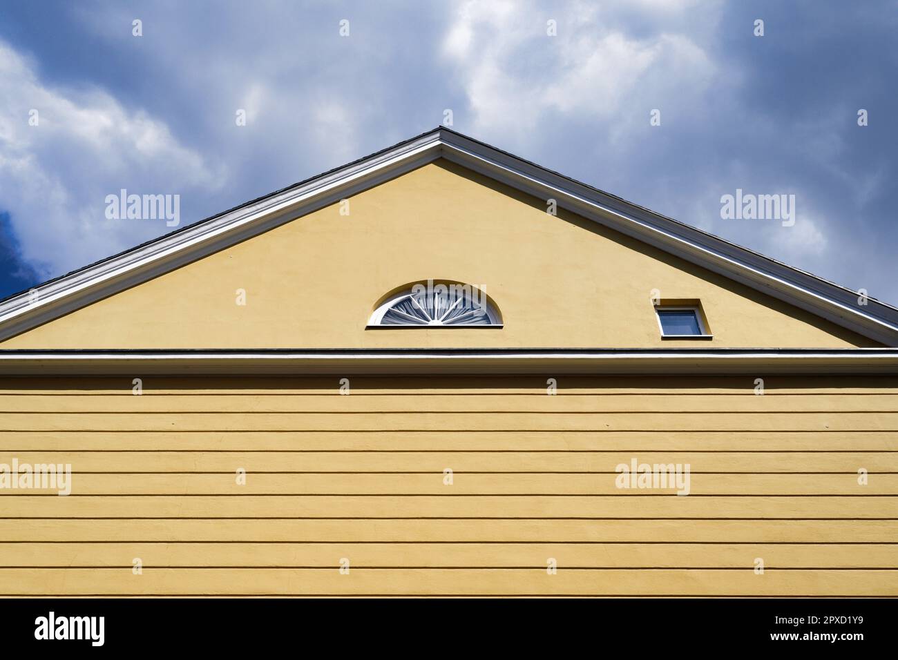 yellow house with gable roof and one semicircular and one square window ...