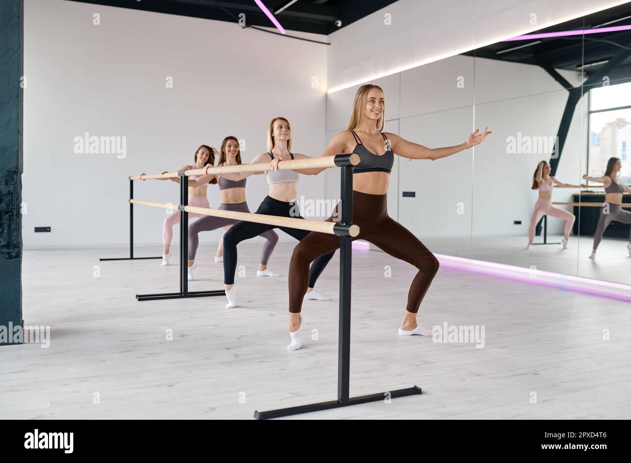 Young smiling female group doing stretching with gym equipment at ...