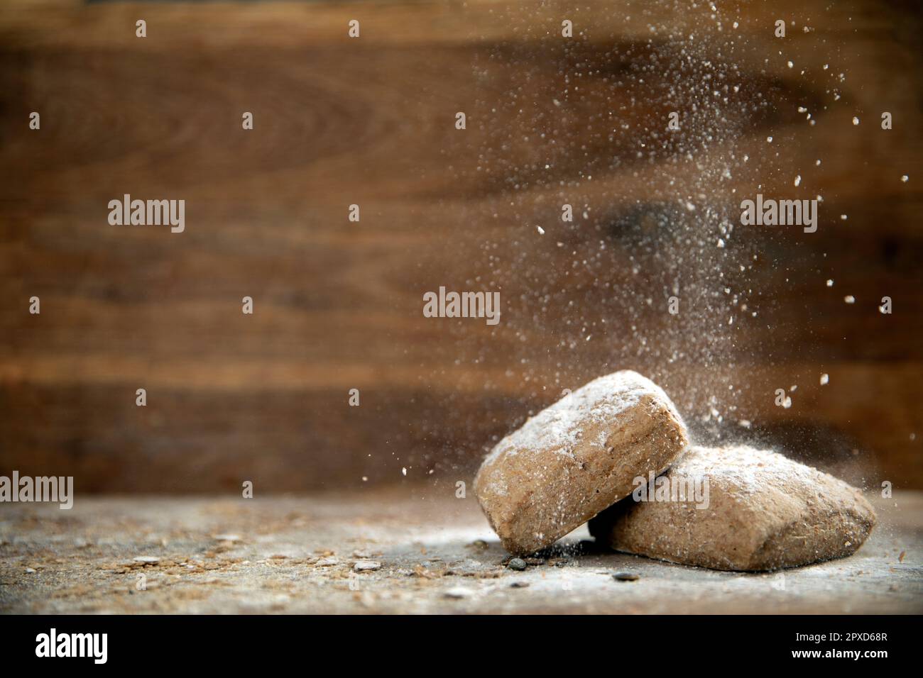 fresh baked whole grain bread on wooden background with falling flour and copy space close up ...