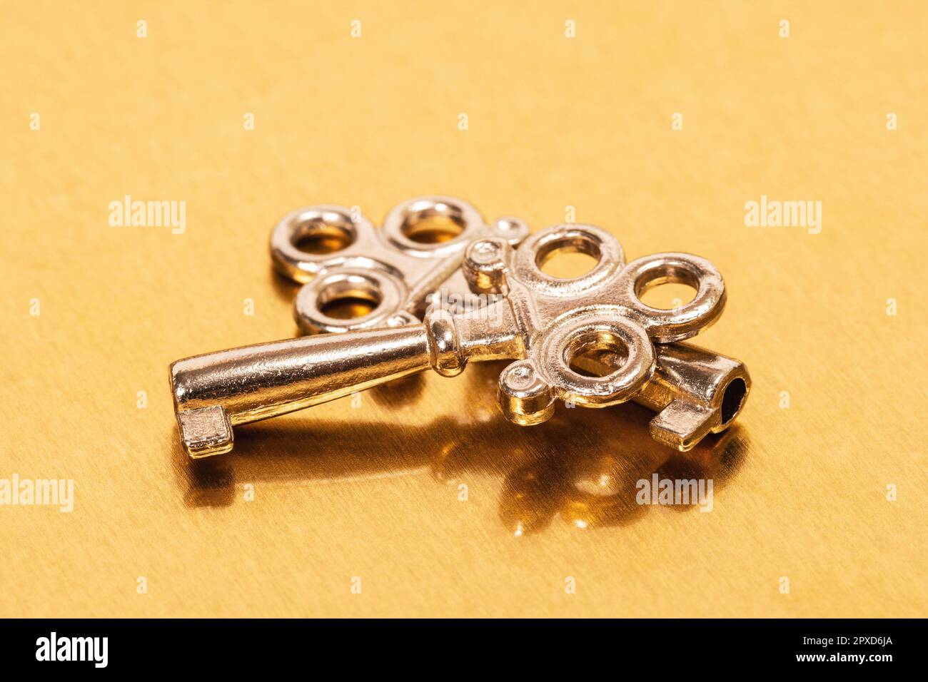 Two small steel keys on golden metal background Stock Photo - Alamy