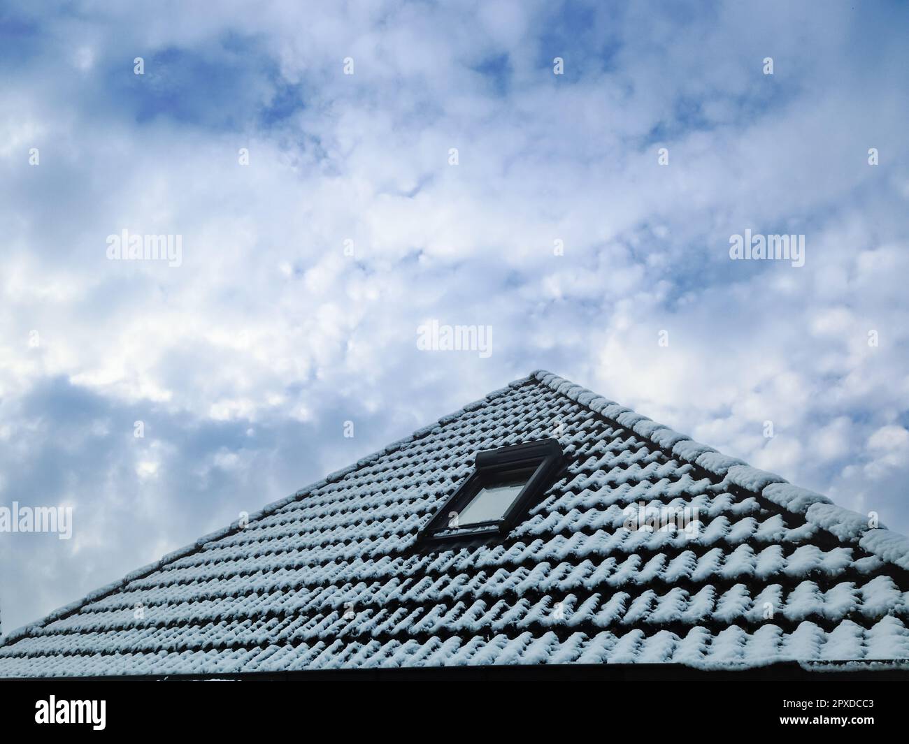 Open roof window in velux style with black roof tiles covered in snow ...