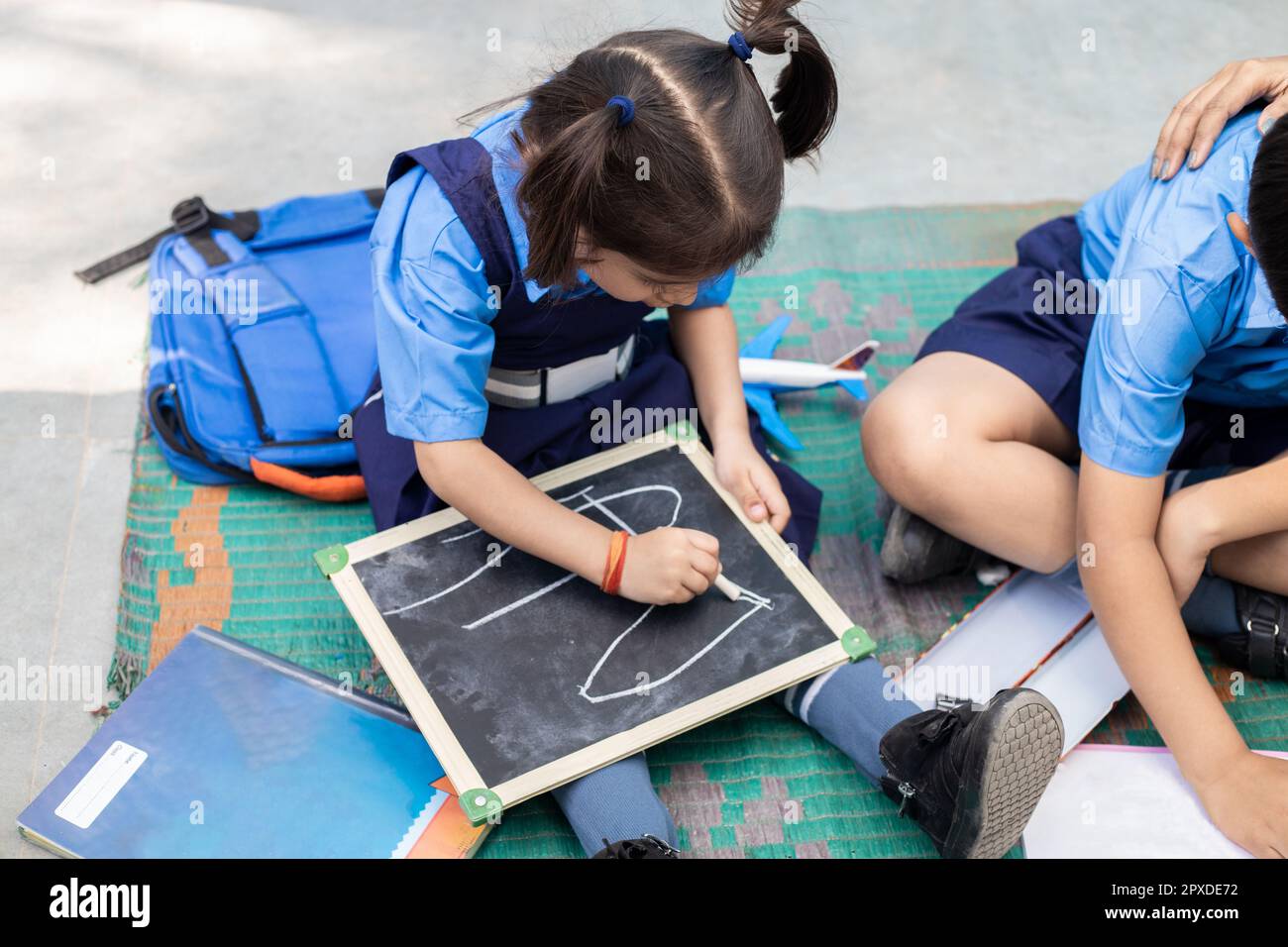 Cute little indian girl student wearing school uniform writing on slate ...