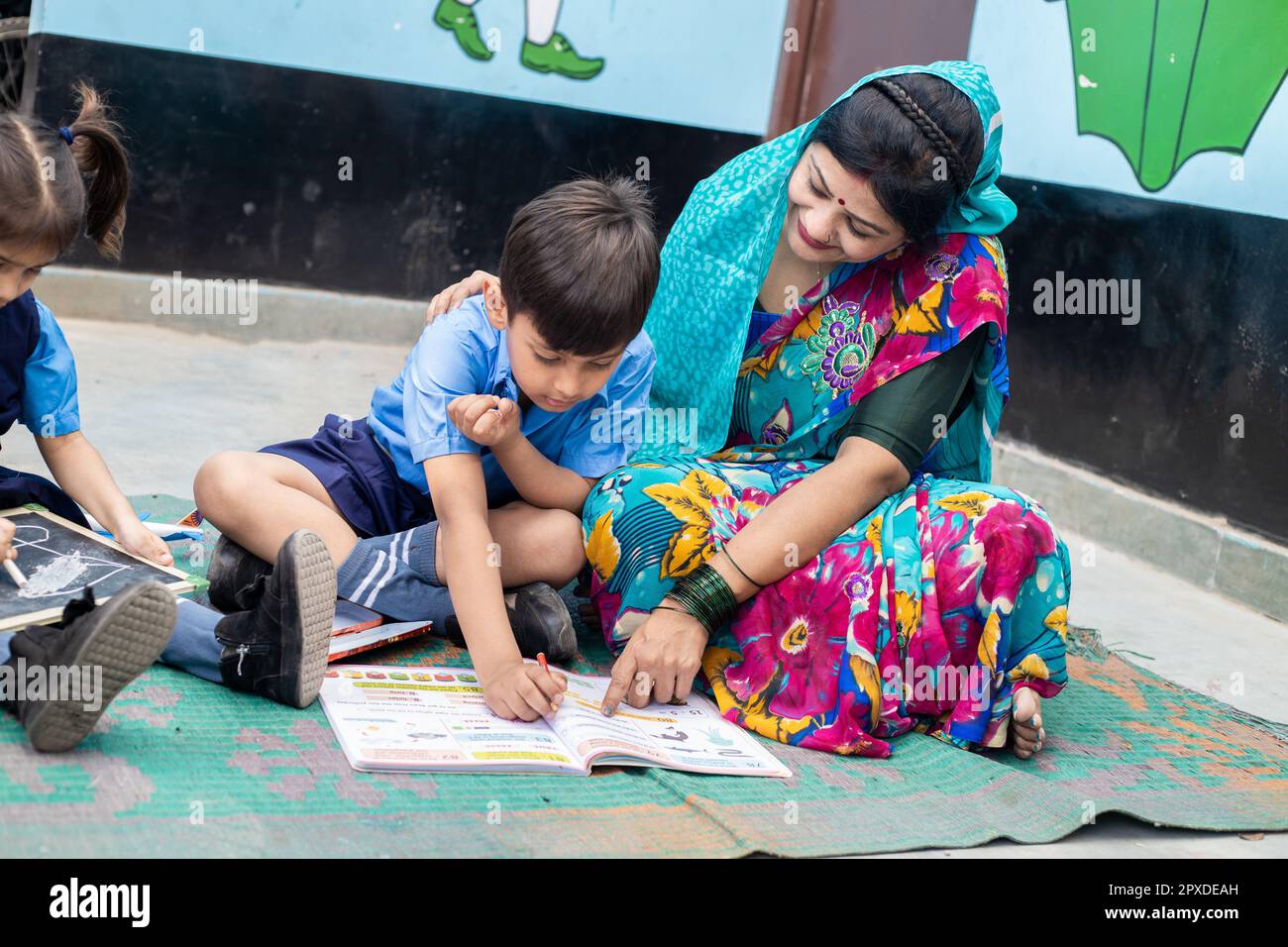 Young indian teacher help little boy student with reading book while ...