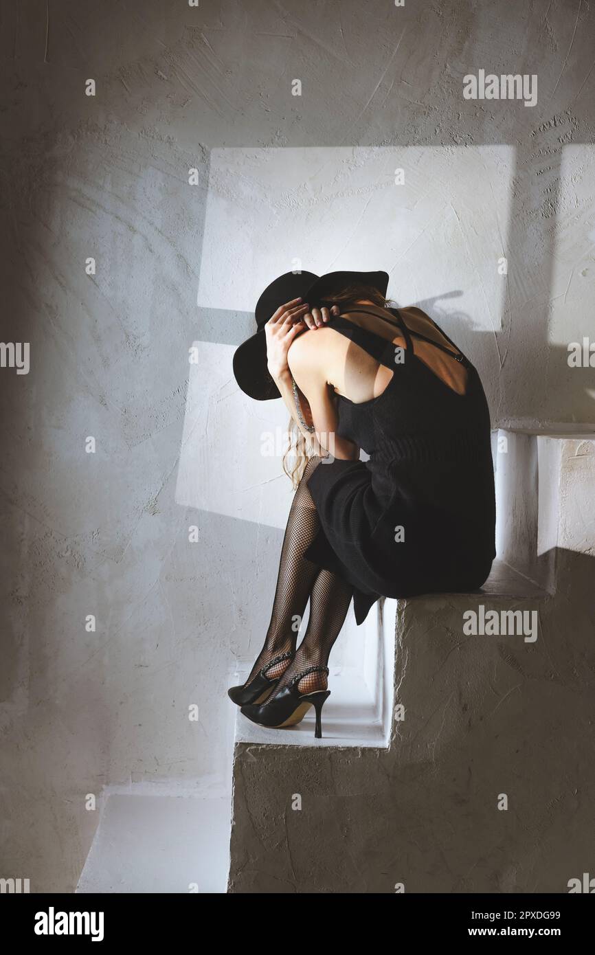 Beautiful woman in depression sit on concrete stairs back to wall ...