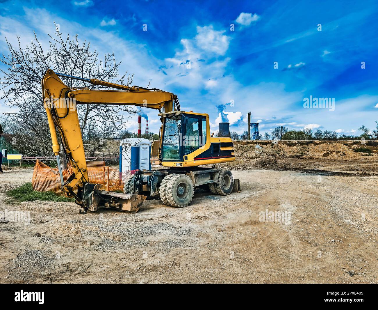 Yellow excavator on an earthen construction site in industrial zone ...