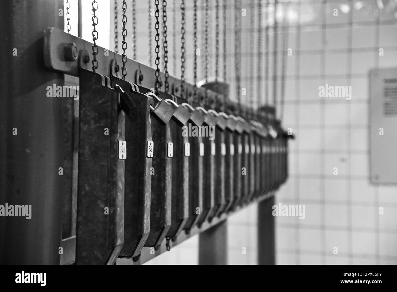 A close-up view of an aged metal jail cell with a chain - grayscale ...