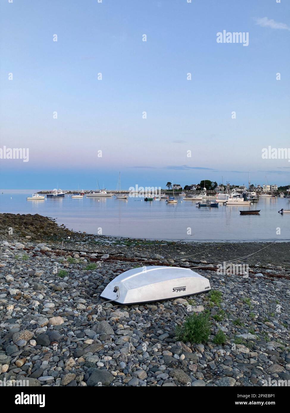 A flipped boat on the rocky shore against the background of the coast ...
