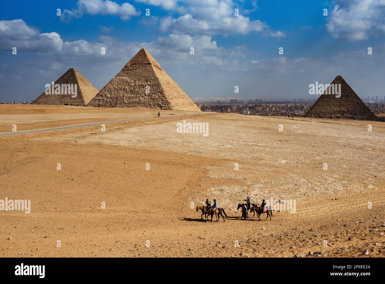 Four people riding horses across a vast desert landscape, with the ...
