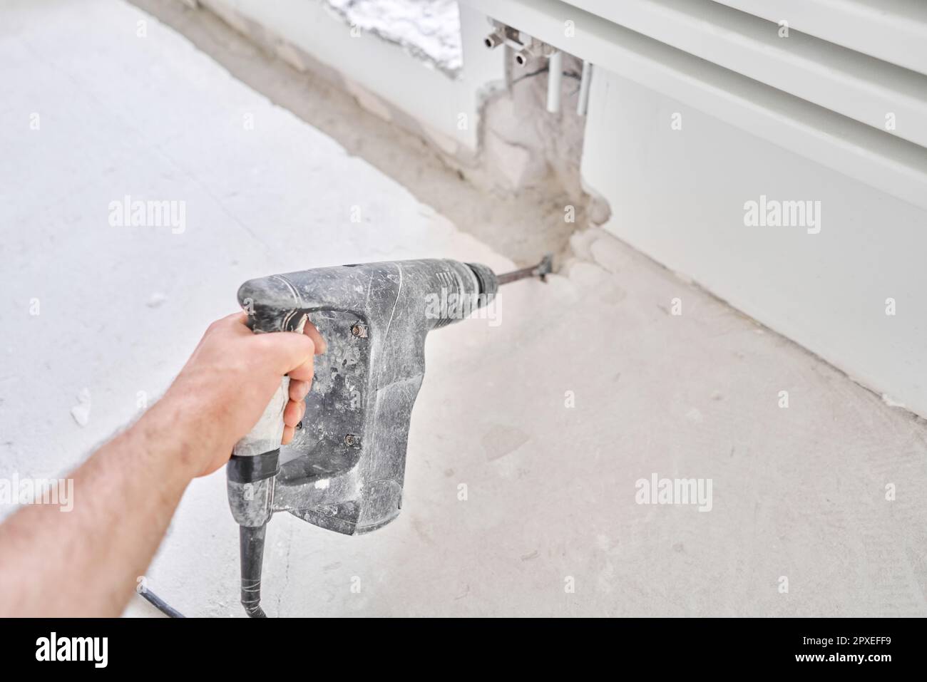 Hammer concrete with a hammer drill to make a hole for heating pipes ...