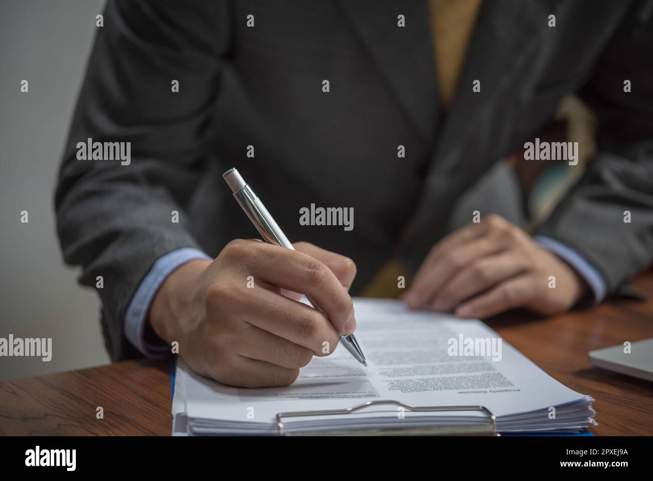 businessman signs documents with a pen making the signature on desk ...
