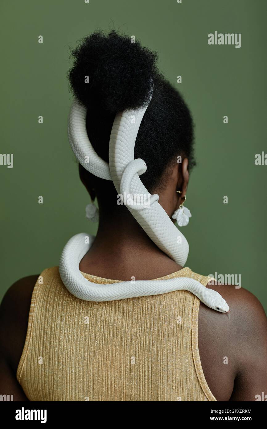 Back view of young African American woman with white rat snake enlacing ...