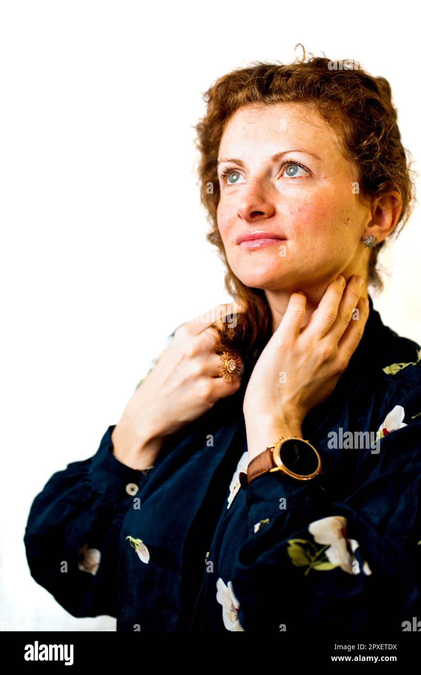 A vertical of a ginger model posing, dressed in an elegant blue shirt ...
