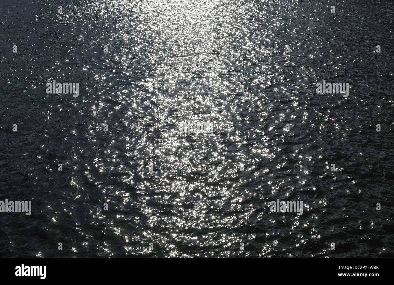 Water surface with waves and ripples and the sunlight reflecting at the ...